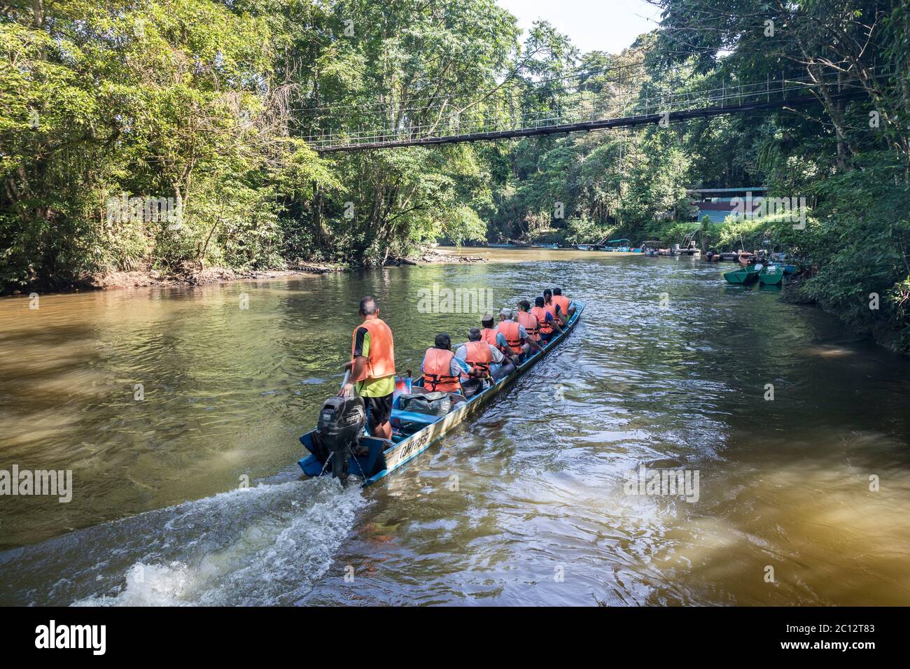 Tourists in longboat going up the Meliau River to the caves, Mulu ...