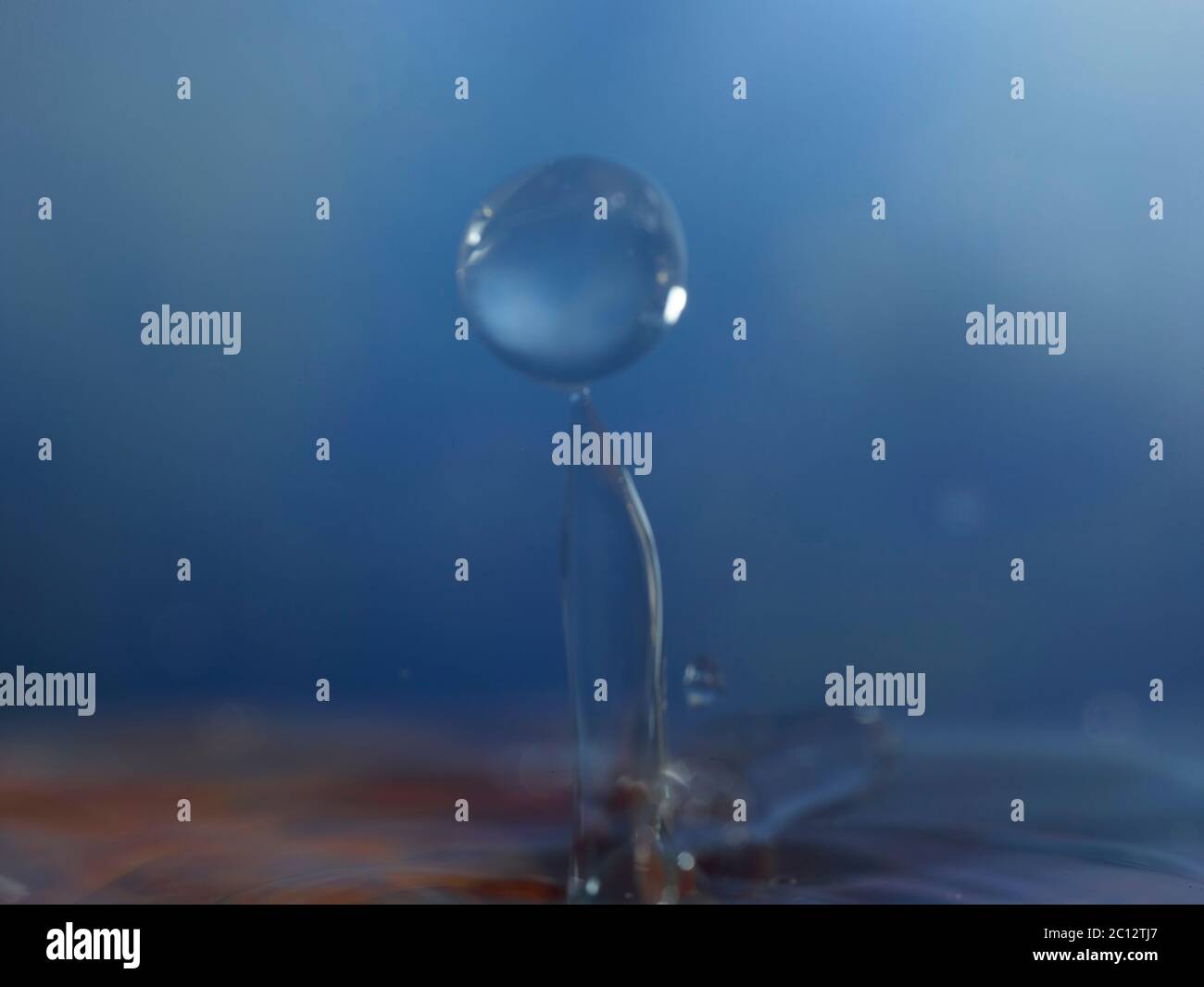 Water droplets falling on and bouncing off a pool of water, leaving ...