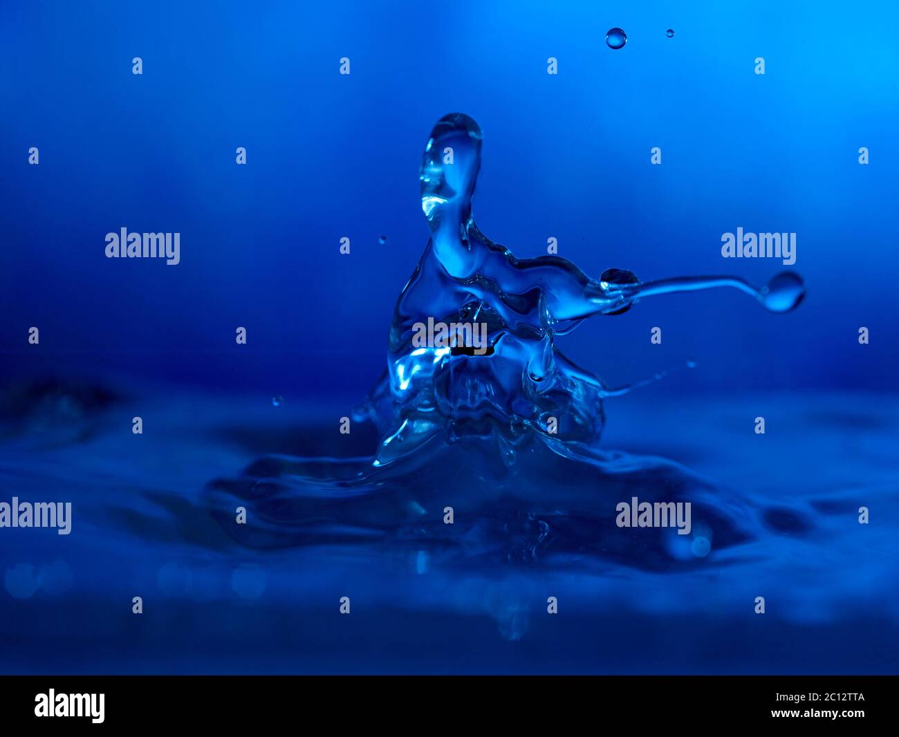 Water droplets falling on and bouncing off a pool of water, leaving ...
