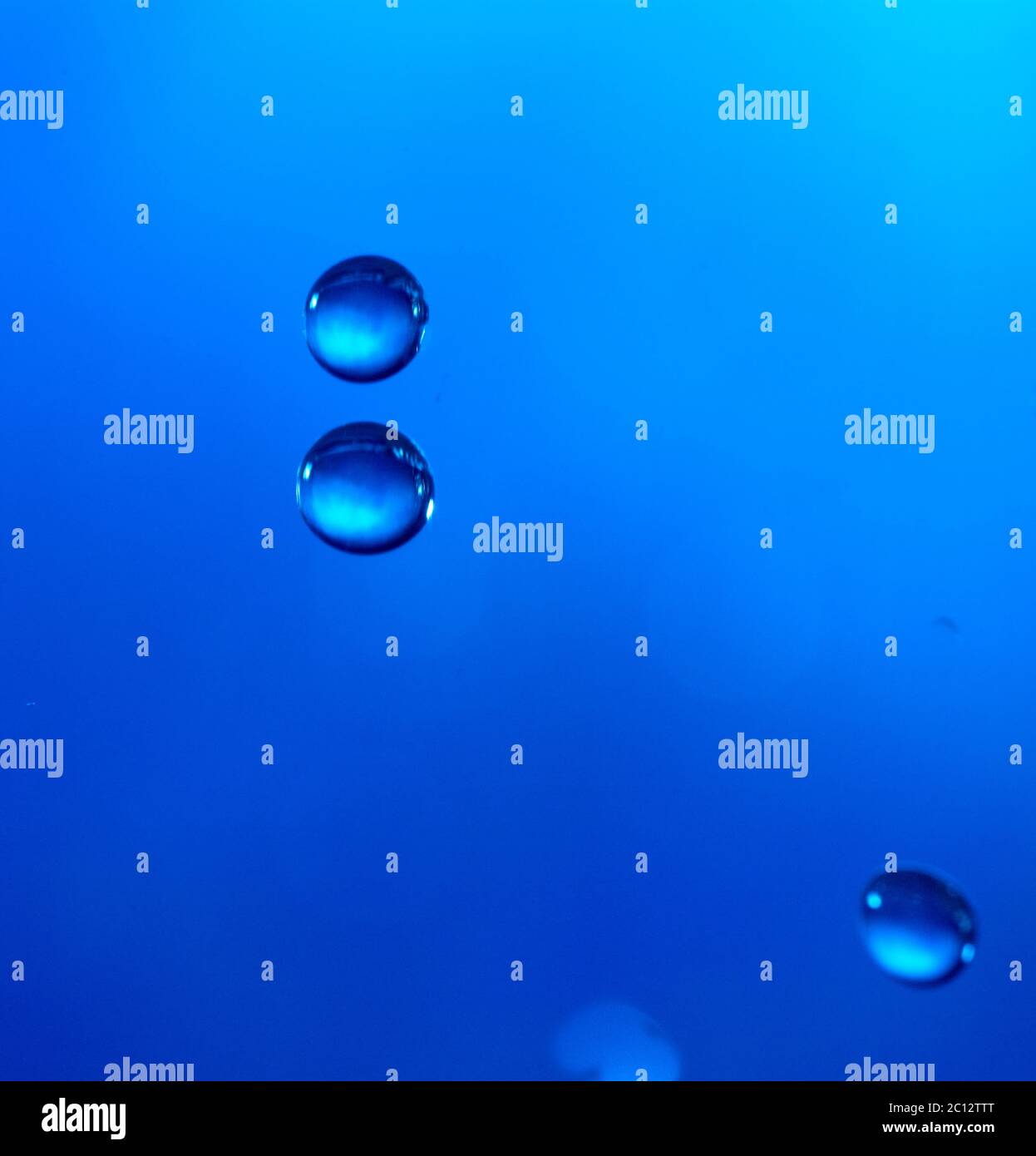 Water droplets falling on and bouncing off a pool of water, leaving ...