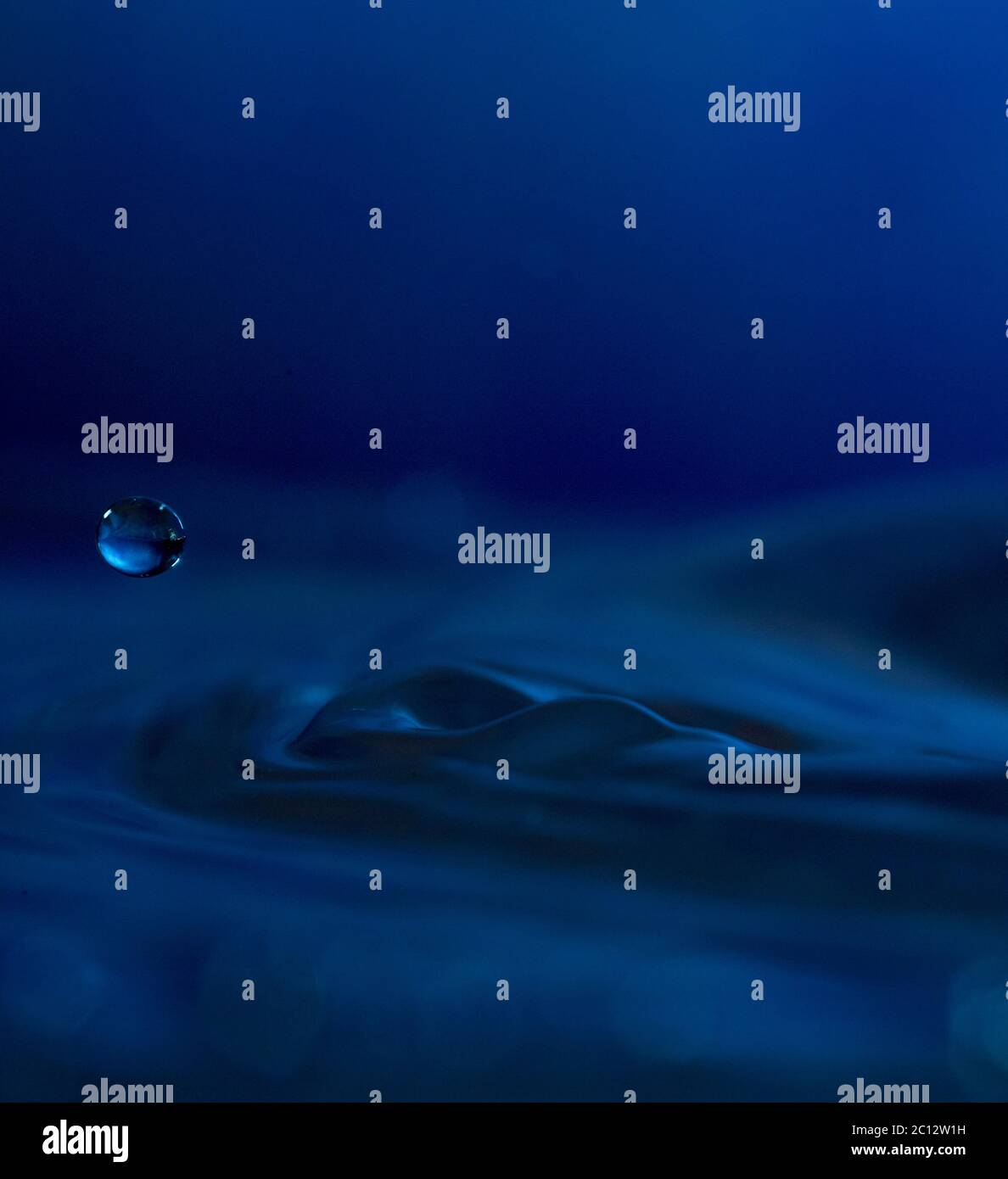 Water droplets falling on and bouncing off a pool of water, leaving ...