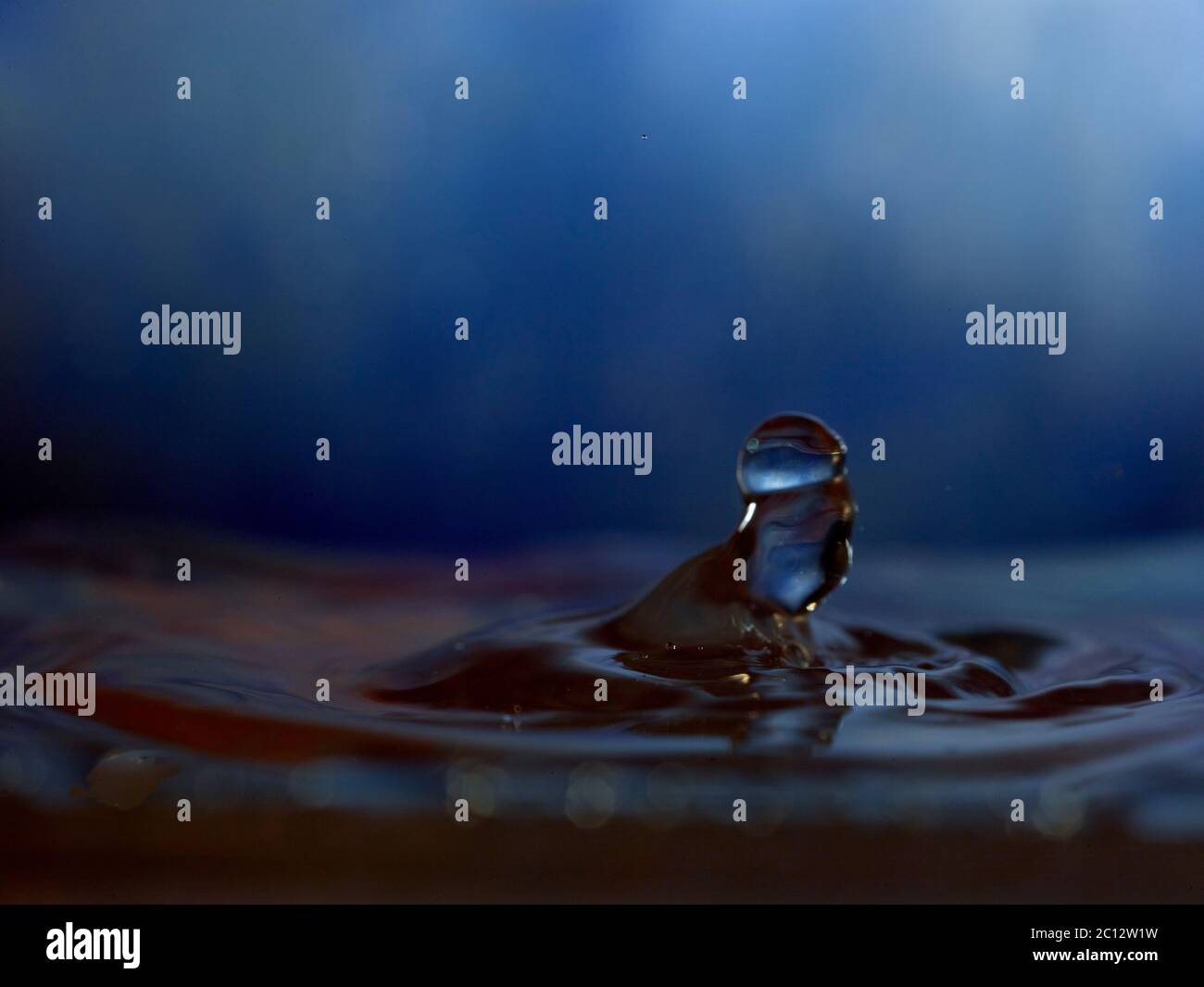 Water droplets falling on and bouncing off a pool of water, leaving ...