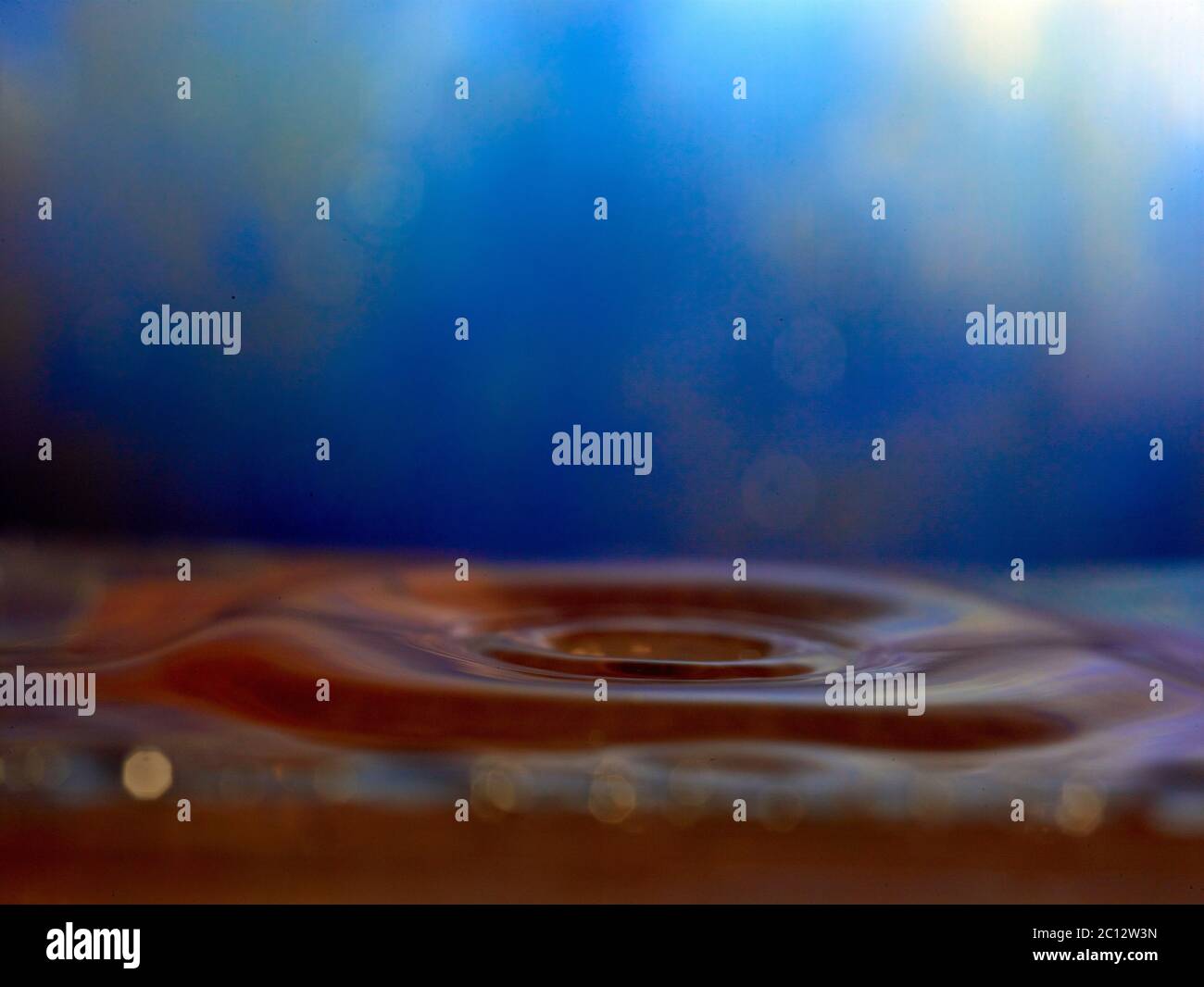 Water droplets falling on and bouncing off a pool of water, leaving ...