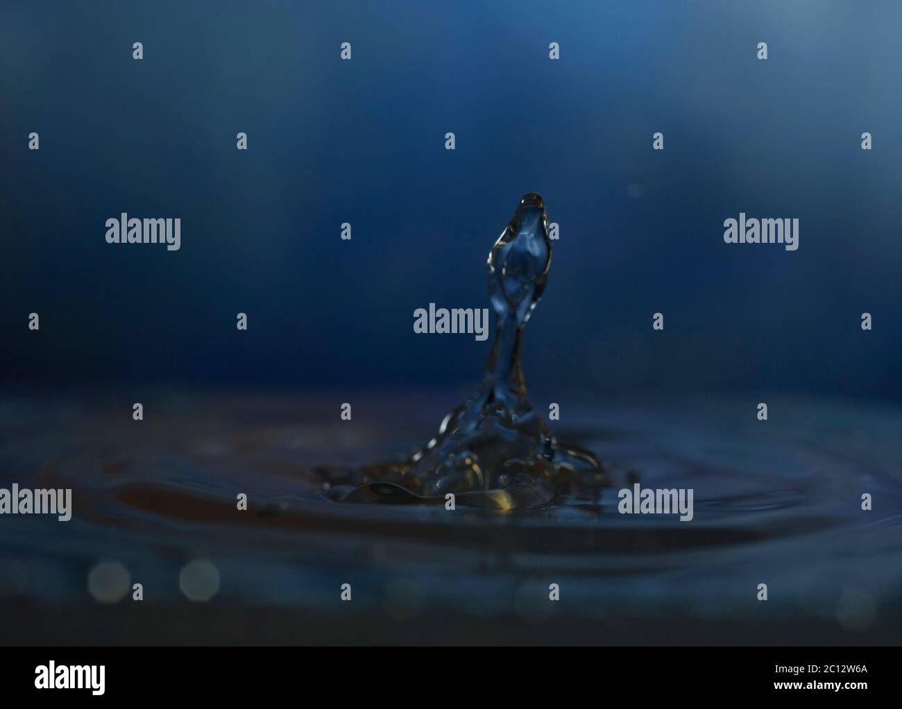 Water droplets falling on and bouncing off a pool of water, leaving ...