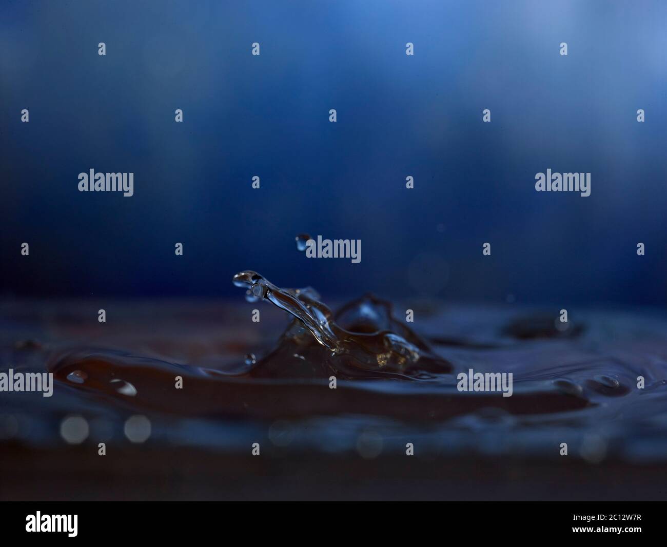 Water droplets falling on and bouncing off a pool of water, leaving ...