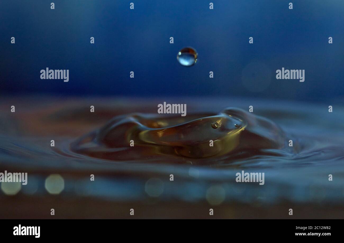 Water droplets falling on and bouncing off a pool of water, leaving ...