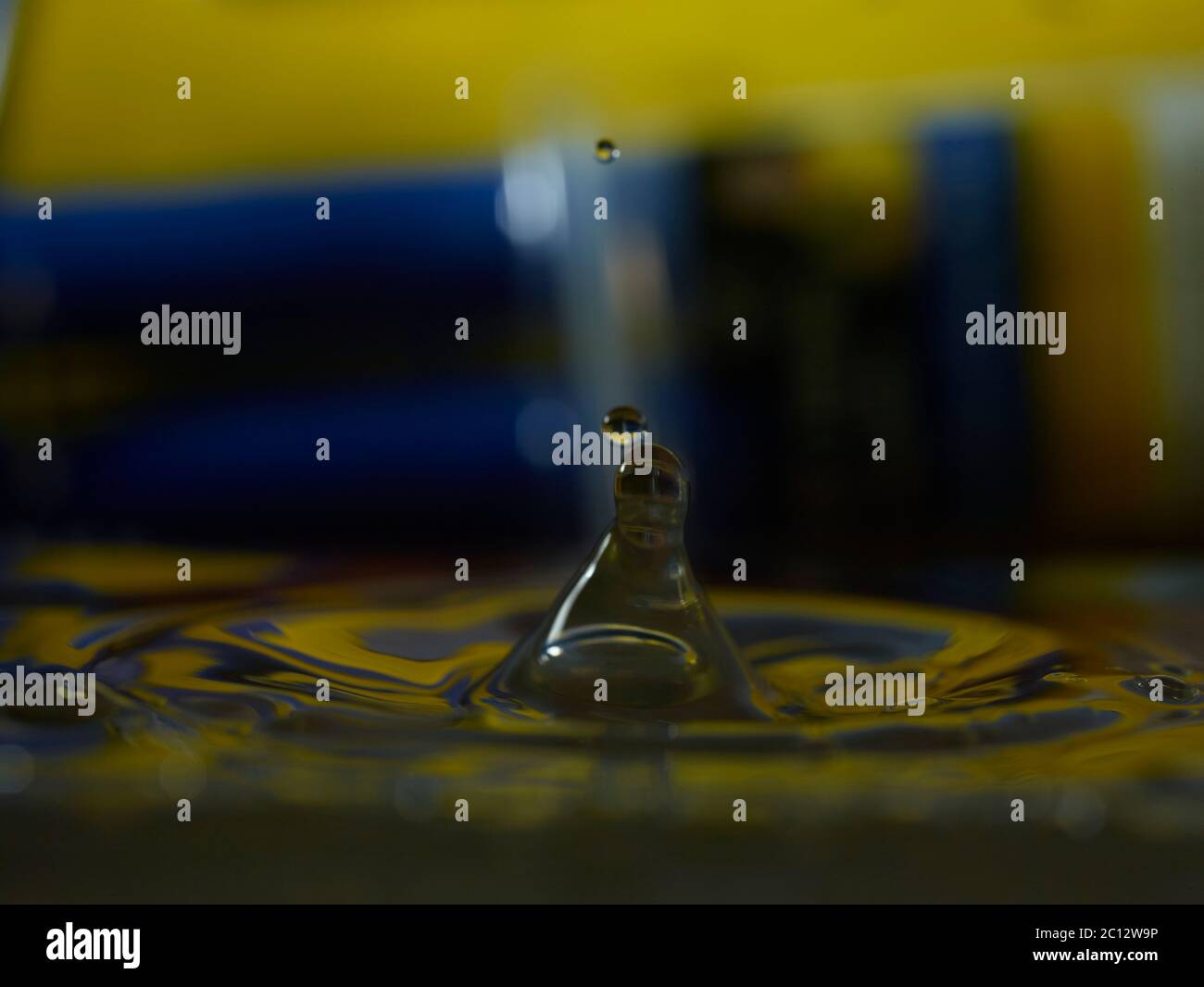 Water droplets falling on and bouncing off a pool of water, leaving ...