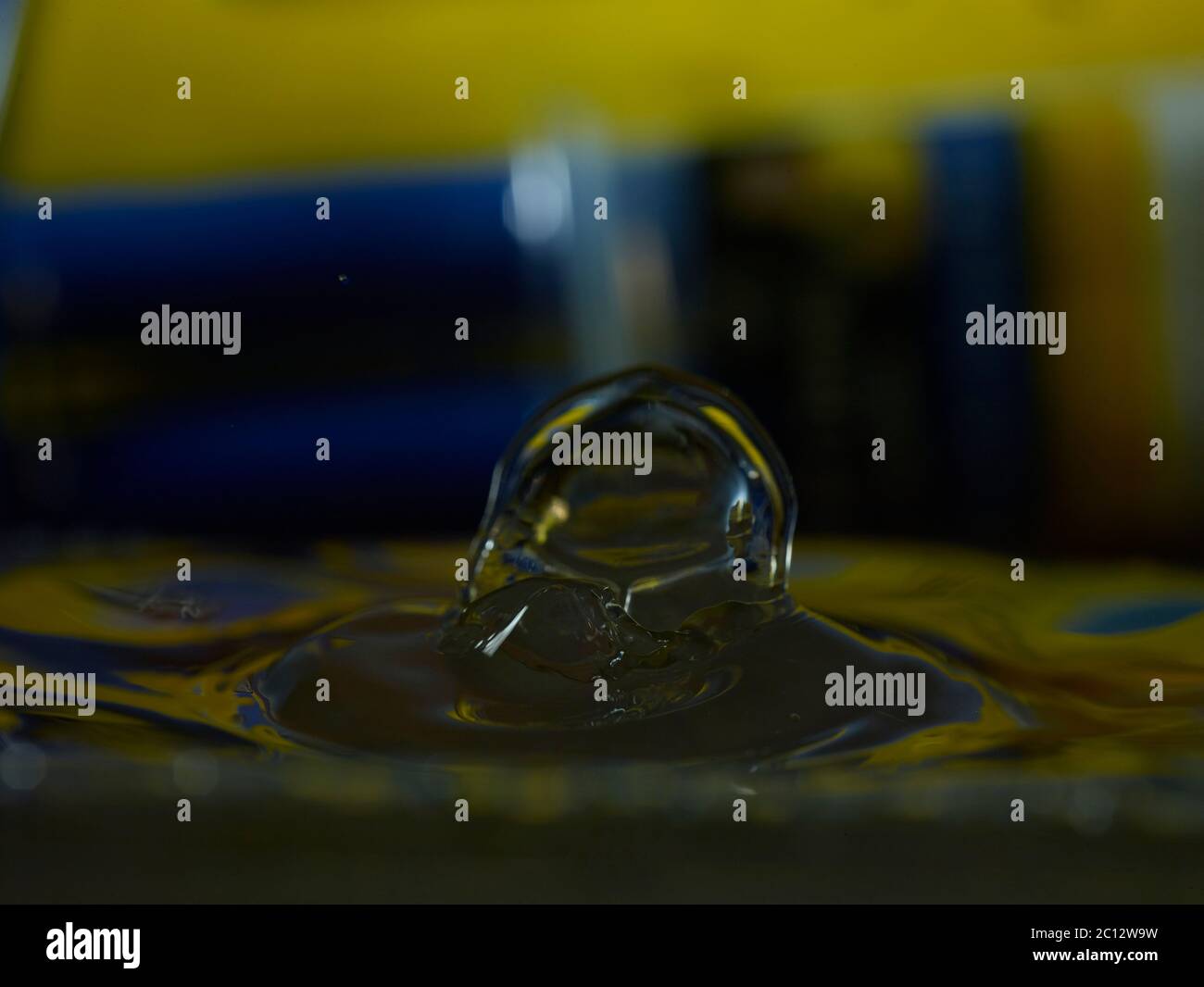 Water droplets falling on and bouncing off a pool of water, leaving ...