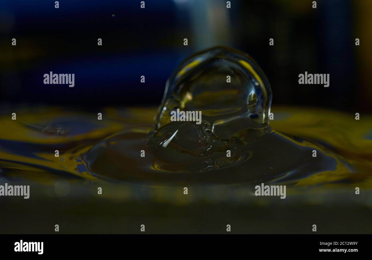 Water droplets falling on and bouncing off a pool of water, leaving ...