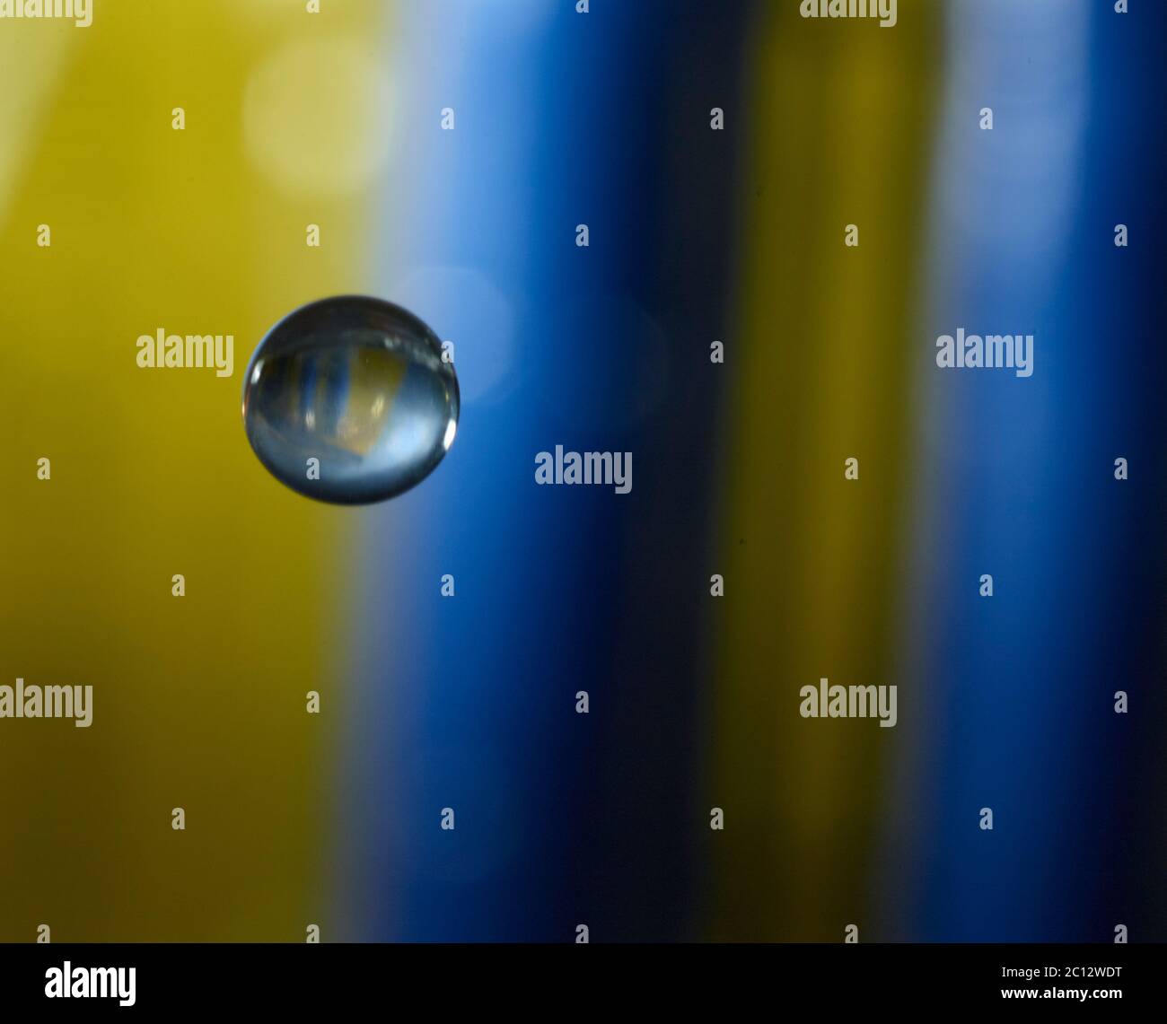 Water droplets falling on and bouncing off a pool of water, leaving ...