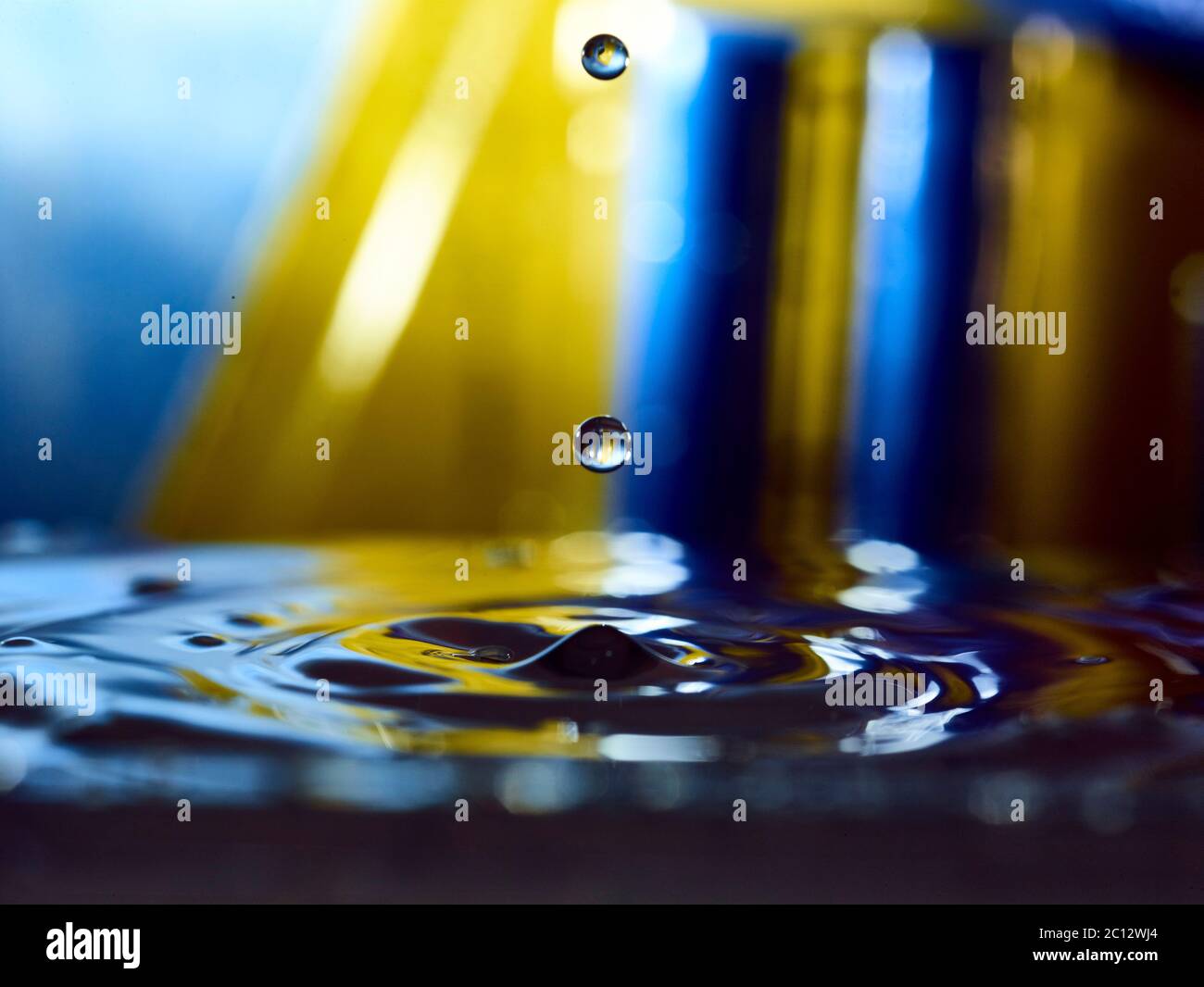 Water droplets falling on and bouncing off a pool of water, leaving ...