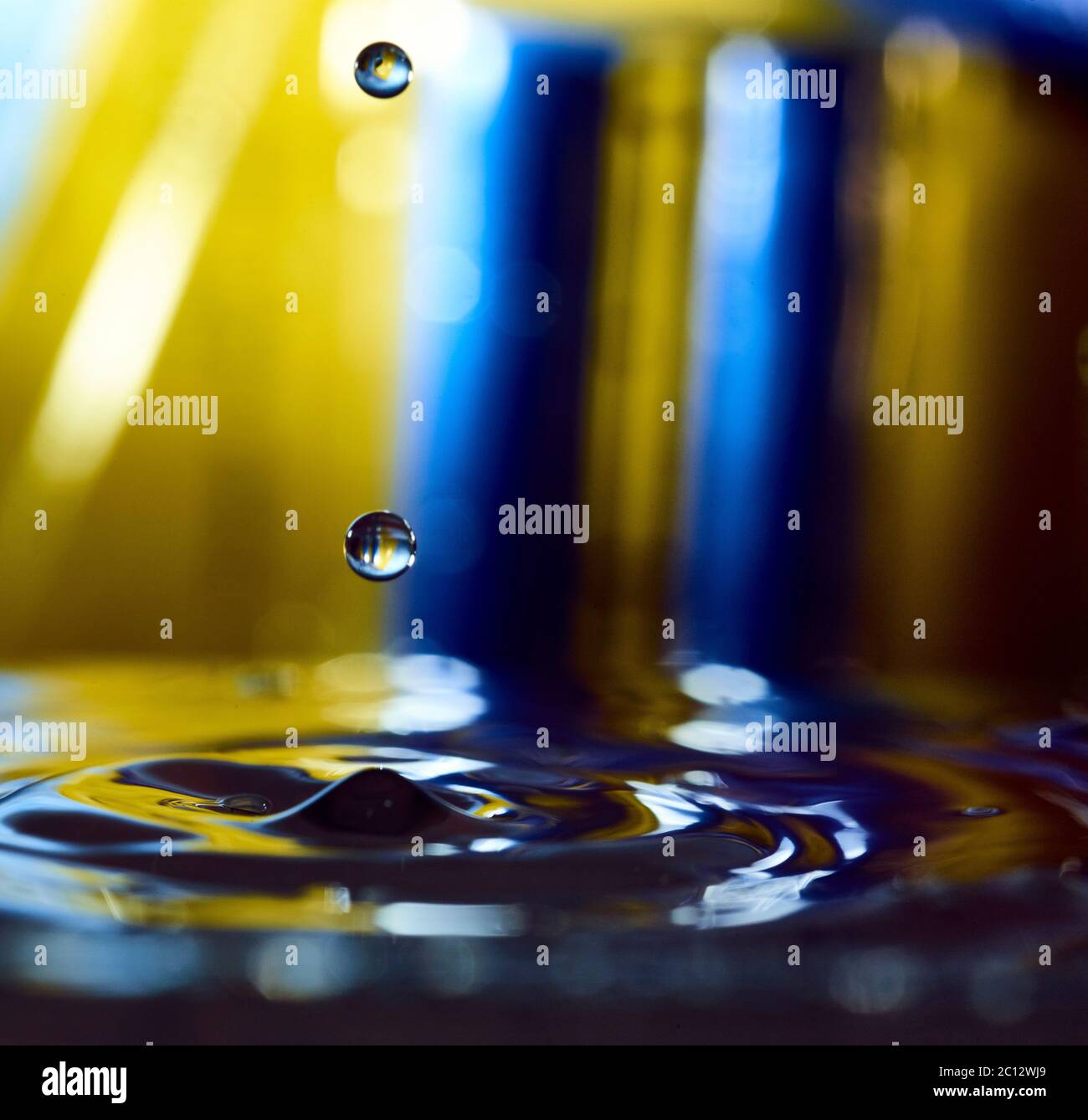 Water droplets falling on and bouncing off a pool of water, leaving ...