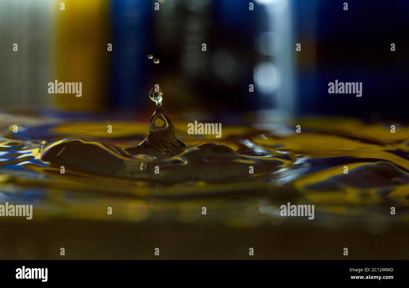 Water droplets falling on and bouncing off a pool of water, leaving ...