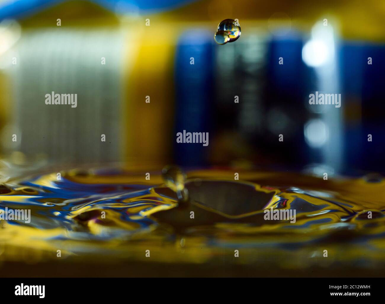 Water droplets falling on and bouncing off a pool of water, leaving ...