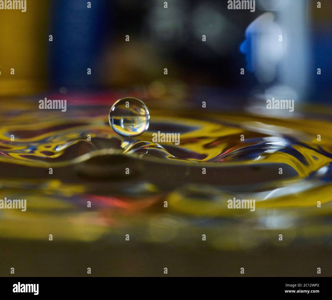 Water droplets falling on and bouncing off a pool of water, leaving ...