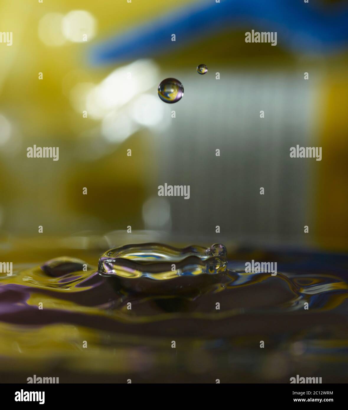 Water droplets falling on and bouncing off a pool of water, leaving ...