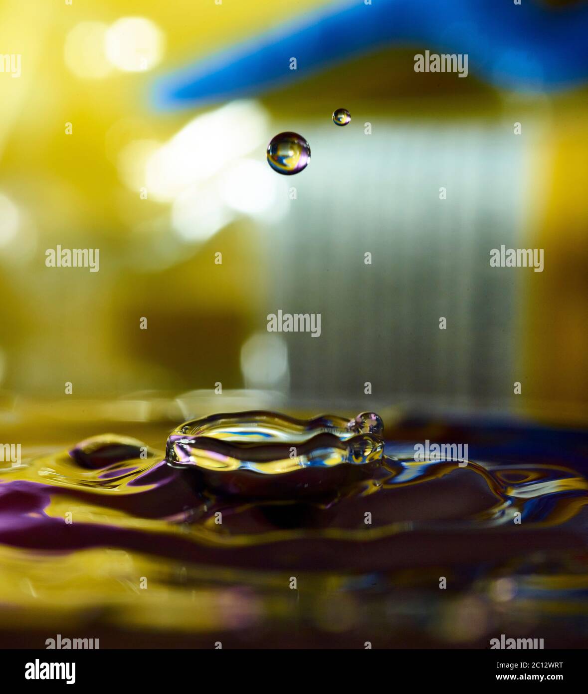 Water droplets falling on and bouncing off a pool of water, leaving ...
