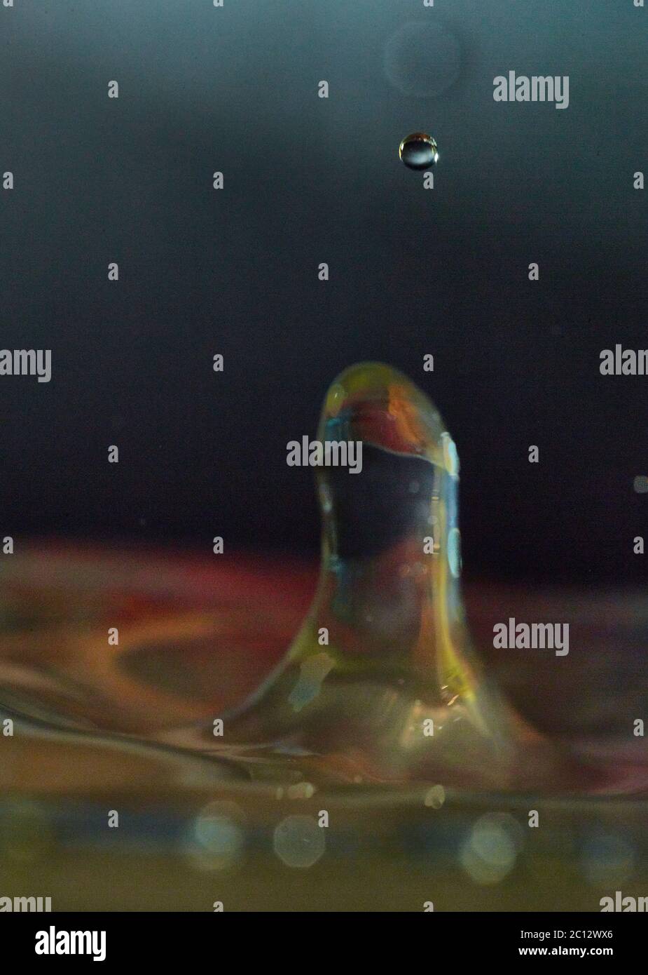 Water droplets falling on and bouncing off a pool of water, leaving ...