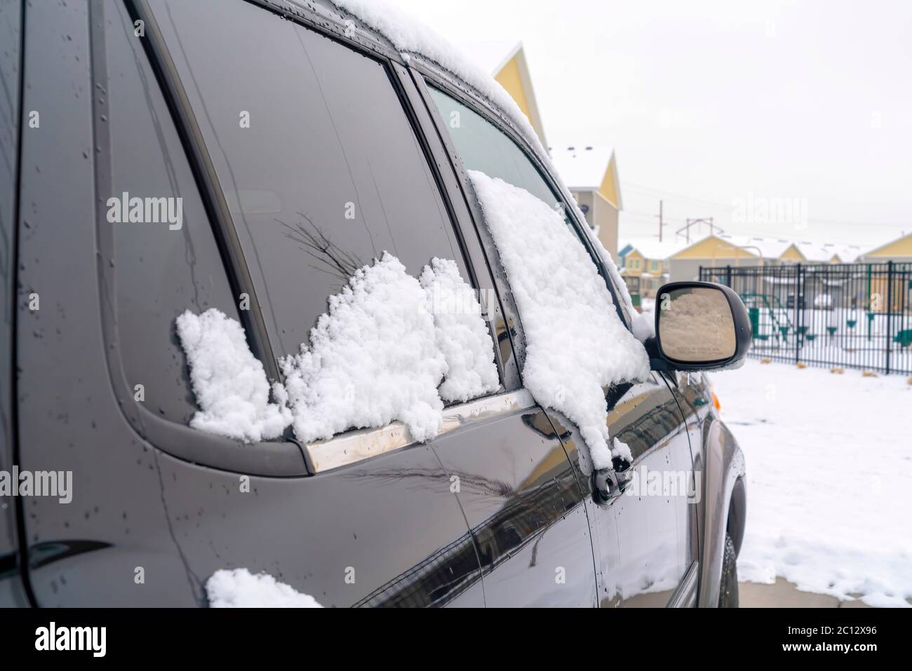 Exterior view of a shiny black car with fresh snow on the tinted ...