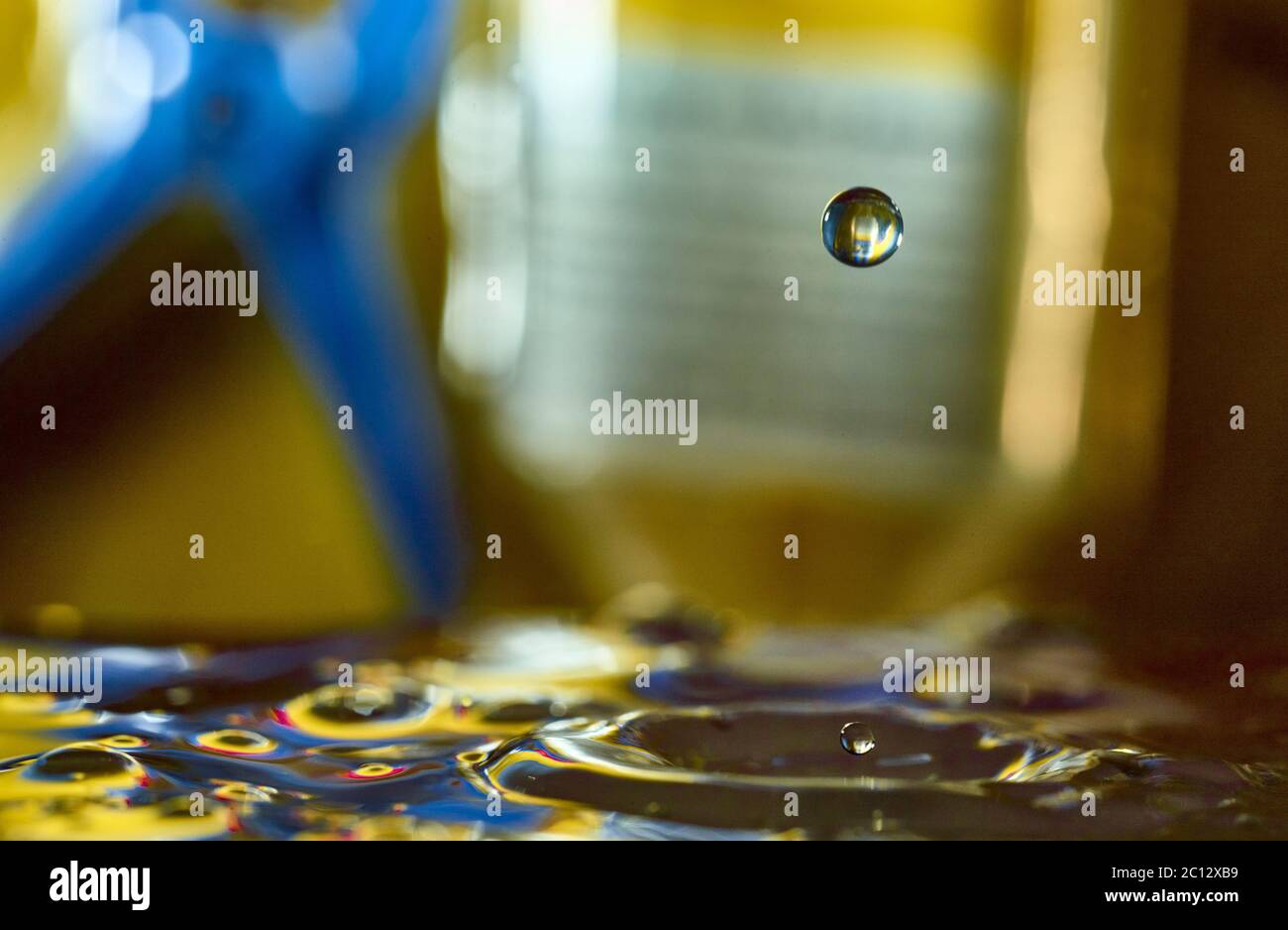 Water droplets falling on and bouncing off a pool of water, leaving ...