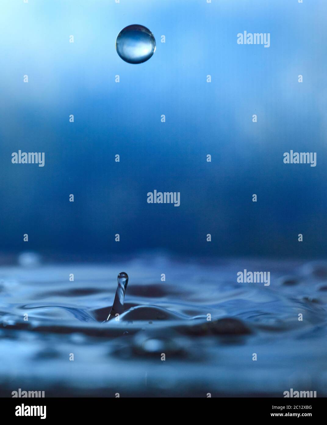 Water droplets falling on and bouncing off a pool of water, leaving ...