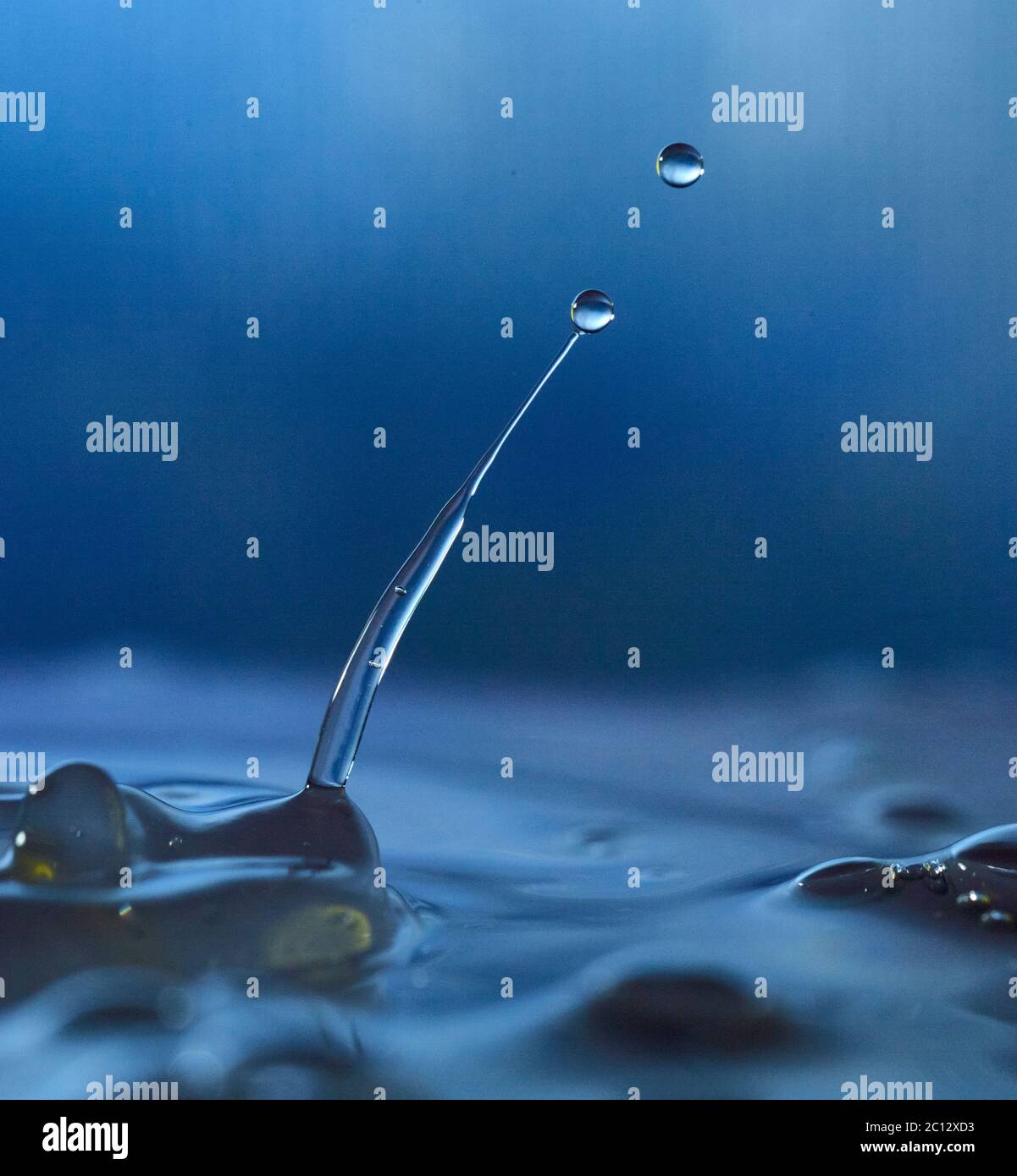 Water droplets falling on and bouncing off a pool of water, leaving ...