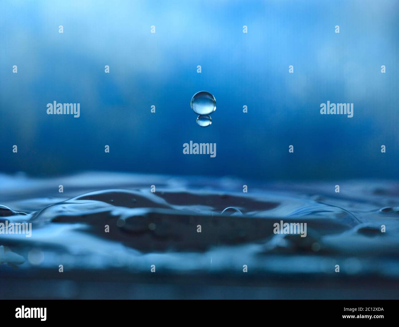 Water droplets falling on and bouncing off a pool of water, leaving ...