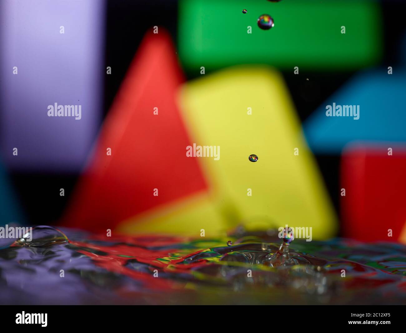 Water droplets falling on and bouncing off a pool of water, leaving ...