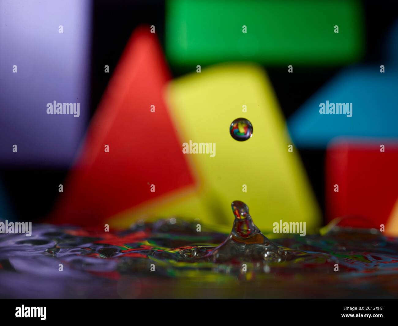 Water droplets falling on and bouncing off a pool of water, leaving ...
