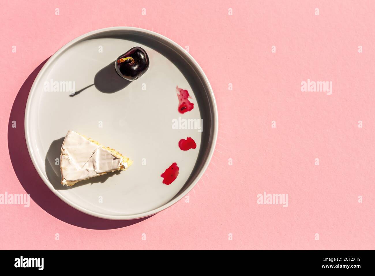 Cherry and one slice of brie cheese on the plate on rose background ...