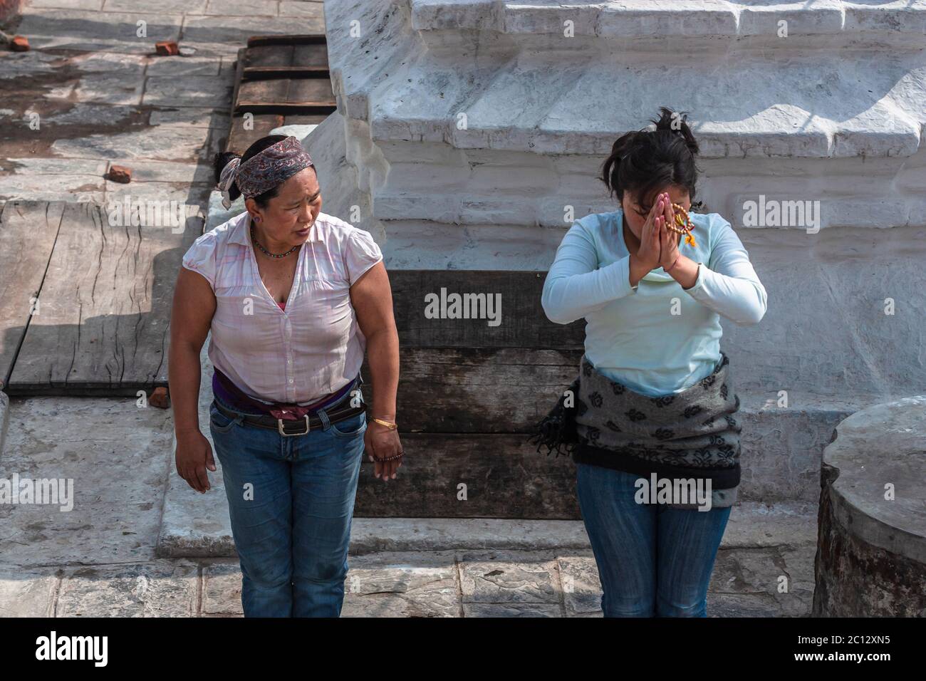 Women pray near temple Stock Photo - Alamy