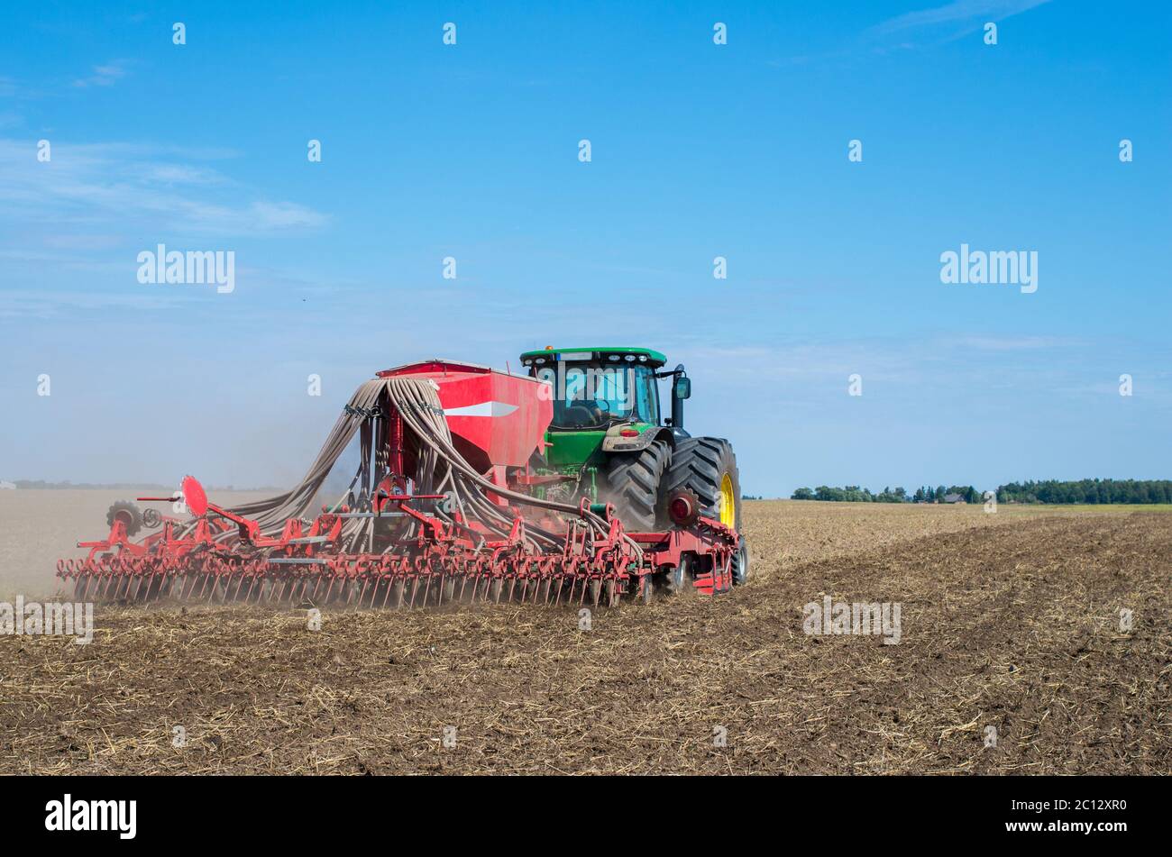 Farm tractor and seeder from the back working in a Lithuanian field ...