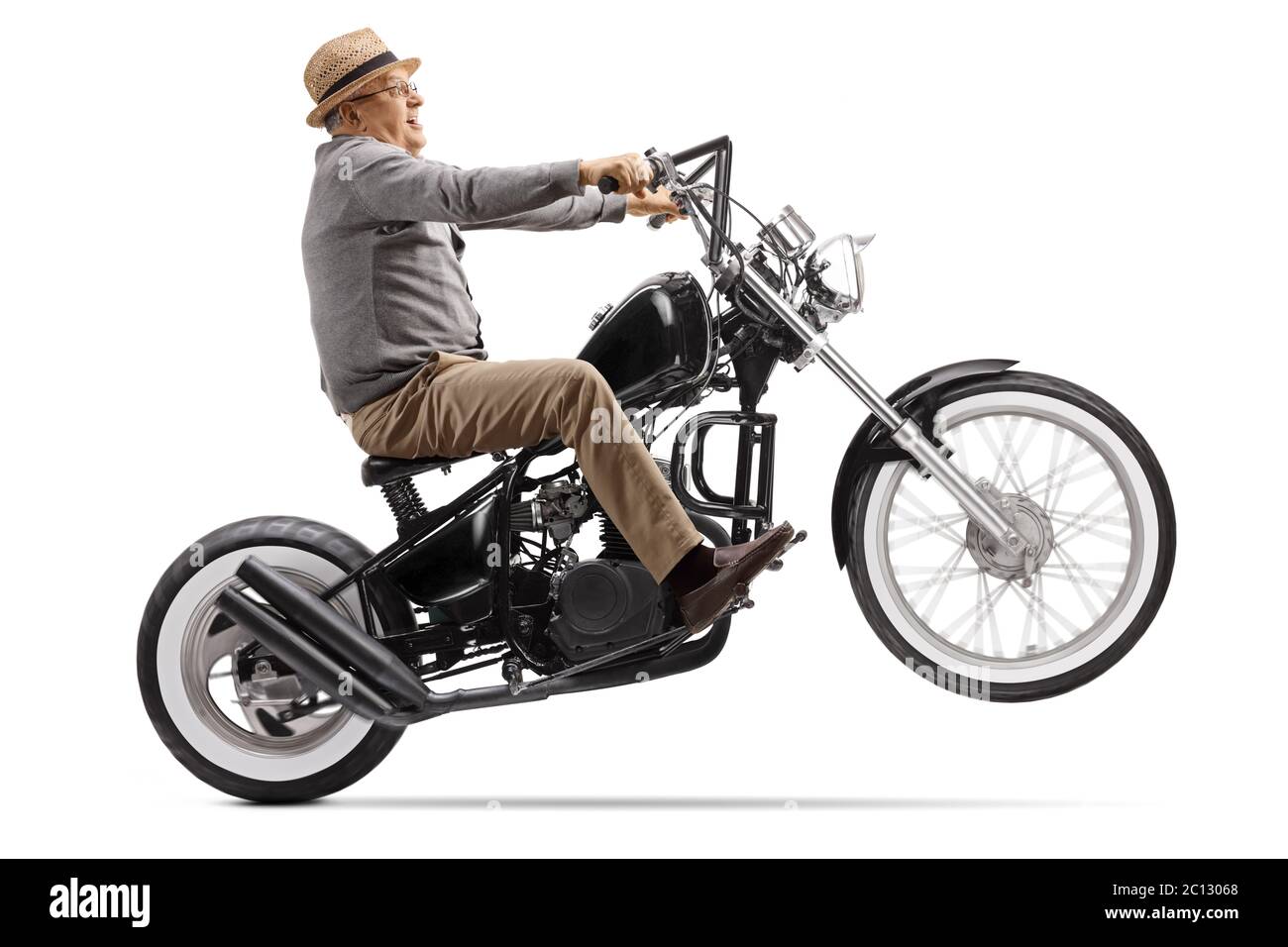 Elderly man rolling a chopper motorbike on the back wheel isolated on ...
