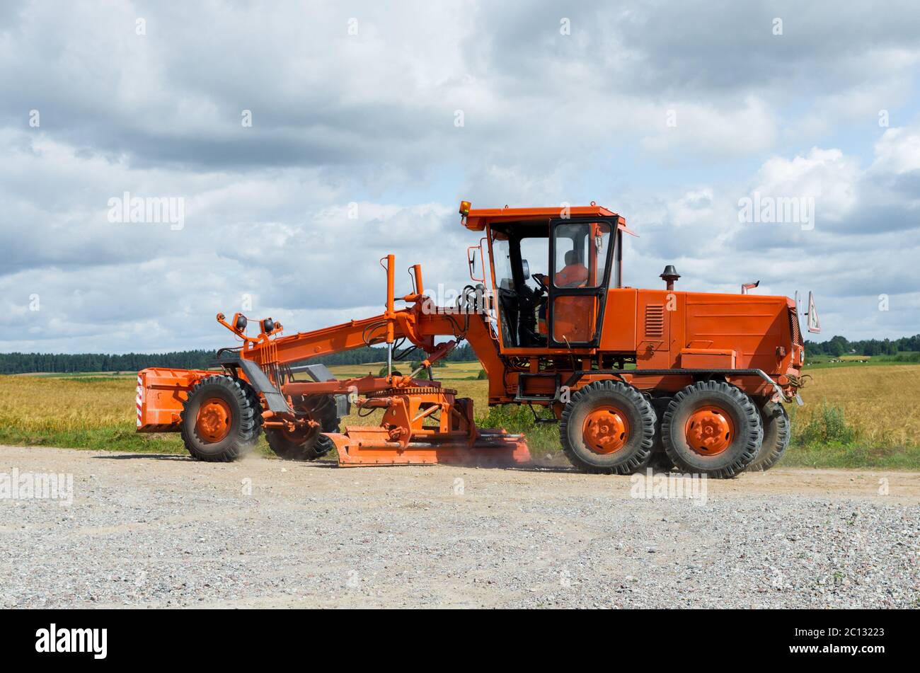 Heavy duty orange road grader machine parks on side of dirt road Stock ...