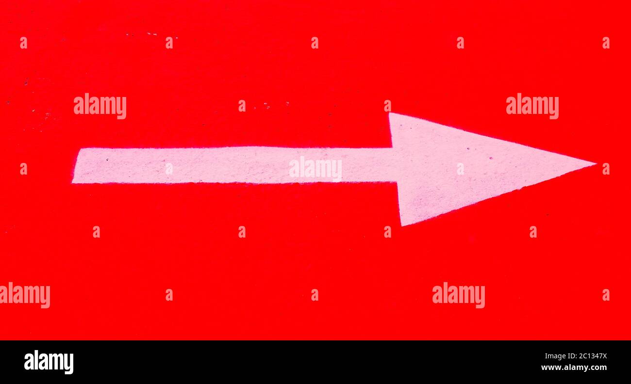White arrow on blood red background painted with luminescent paint ...