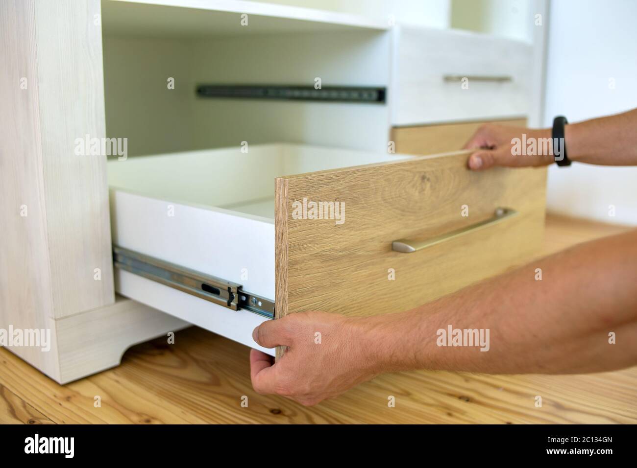 Close up of carpenter hands installing wooden drawer on sliding skids ...
