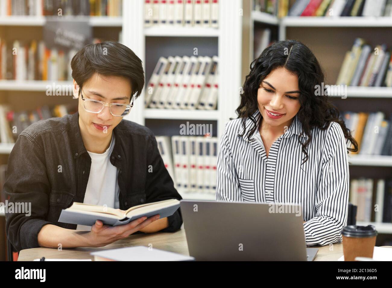 Two smiling multicultural students learning at public library Stock ...