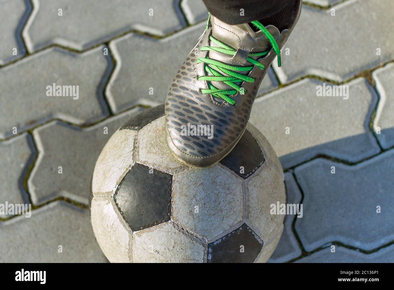 Close-up of boy foot in sport shoes on football ball outdoors on sunny ...