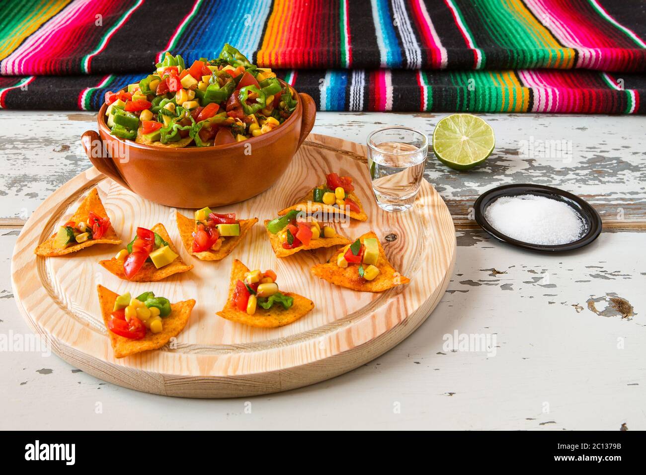 Nachos chips and vegetables in an earthenware bowl and tequila with a ...
