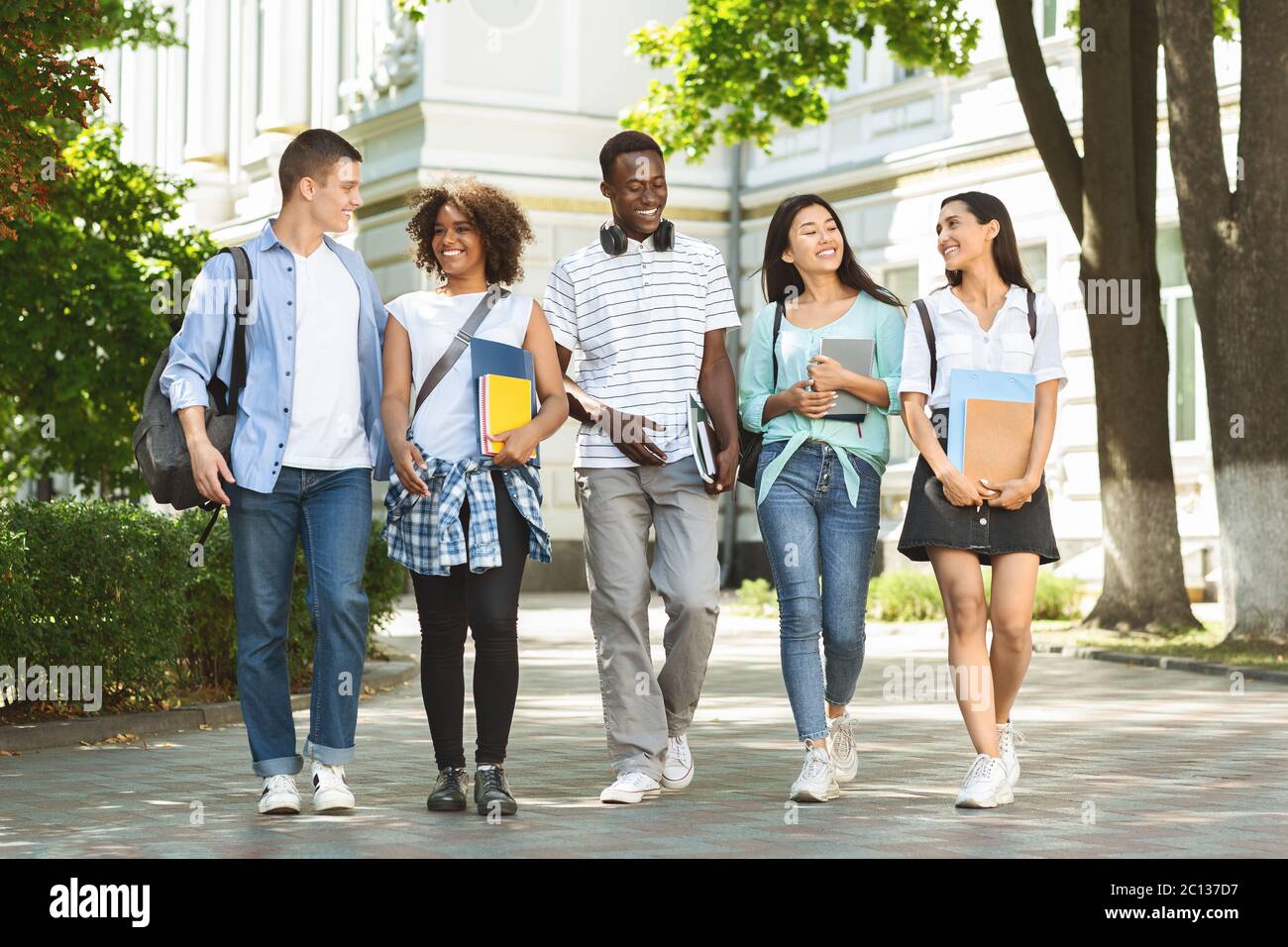 Students communication. Group of college friends walking outdoors in ...