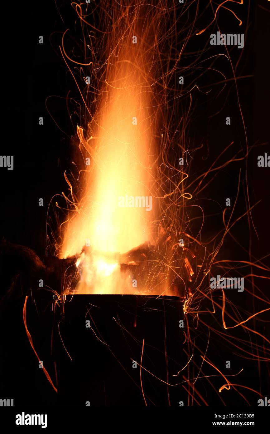 Flames of fire and sparks from firewood burning in a metal outside ...