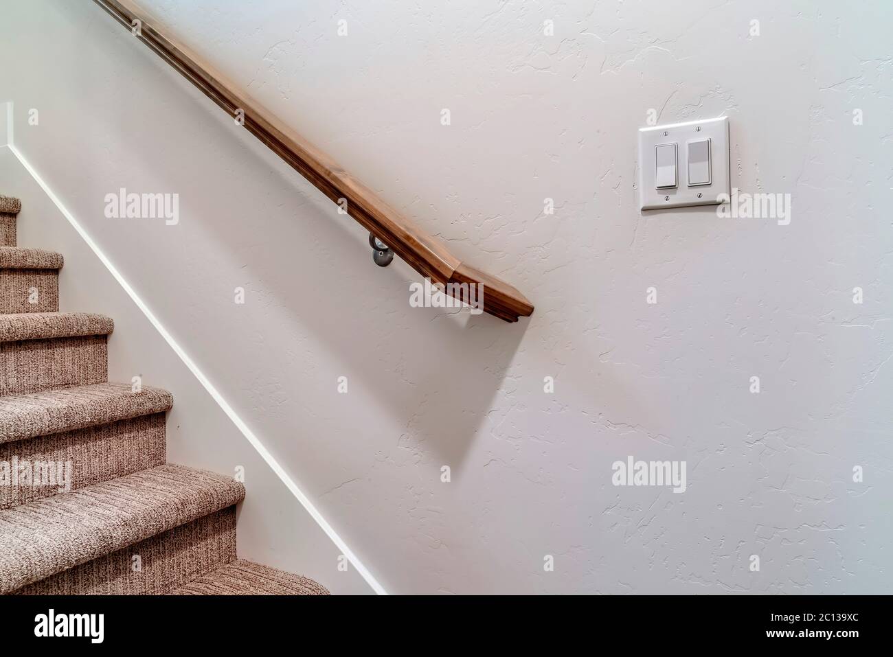 Brown wood handrail of staircase and rocker light switch against ...