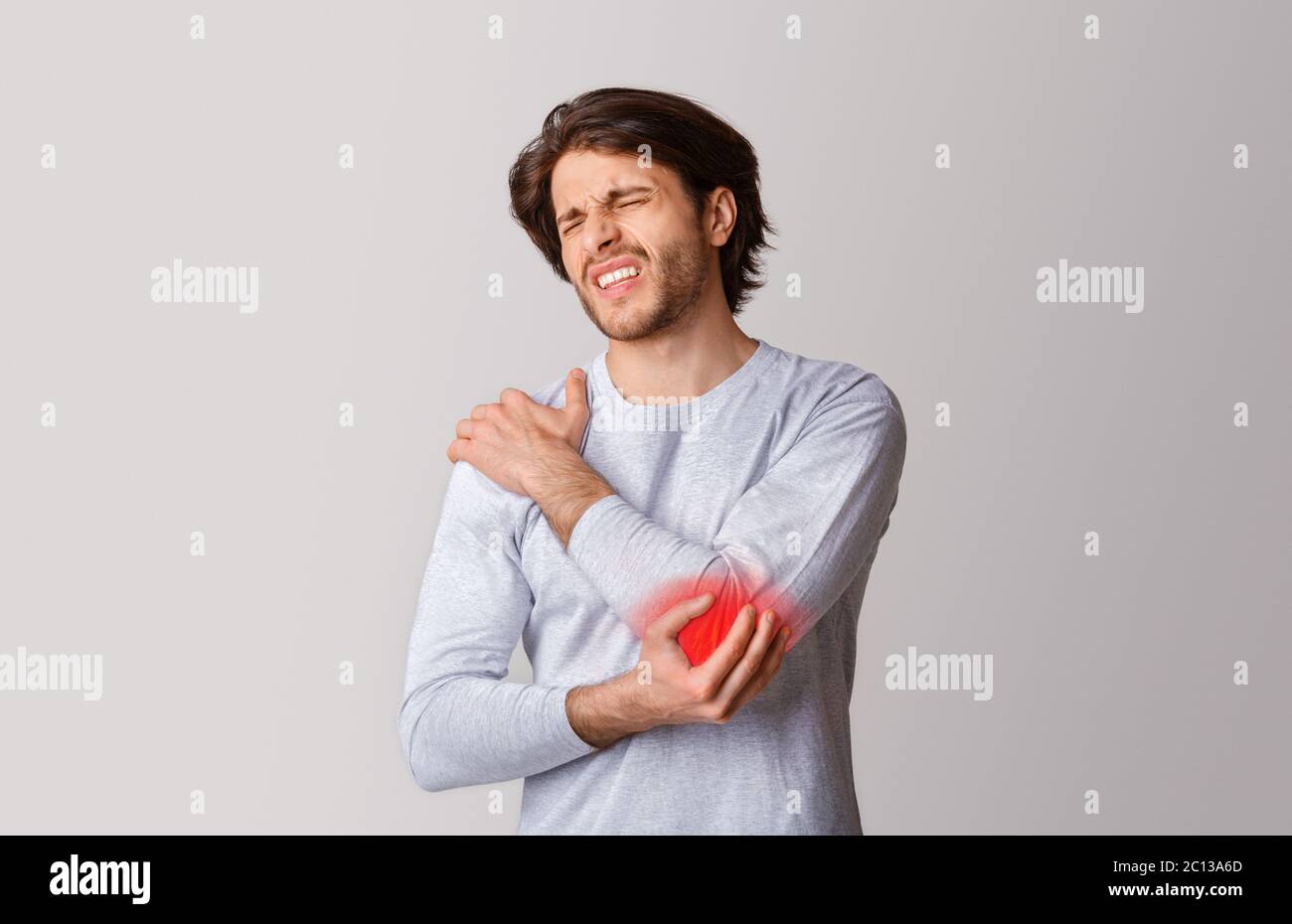 Elbow inflammation. Man expresses pain in his face and holds to red ...