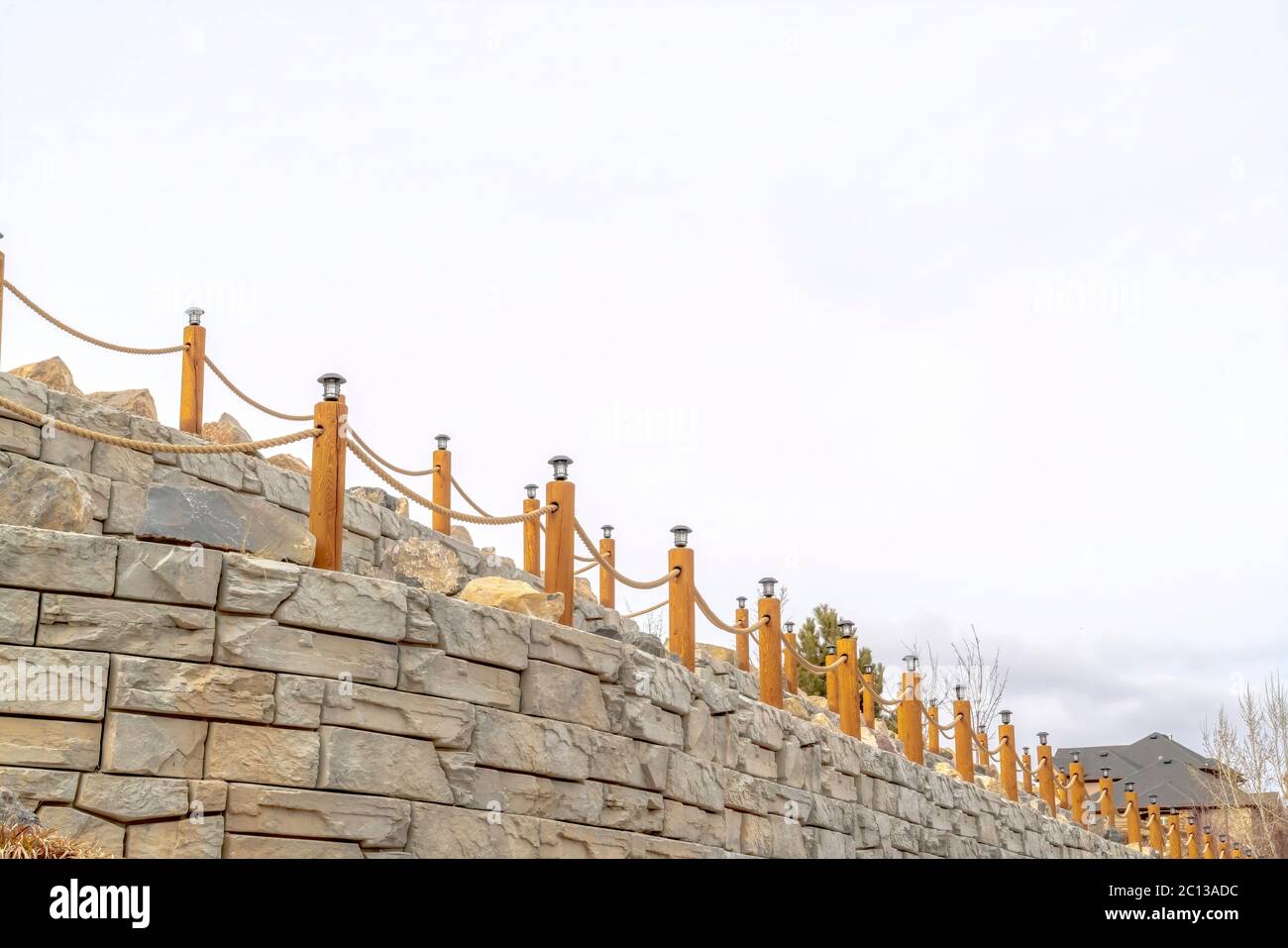 Rope fence with lamps on posts lining a retaining wall made of stone ...