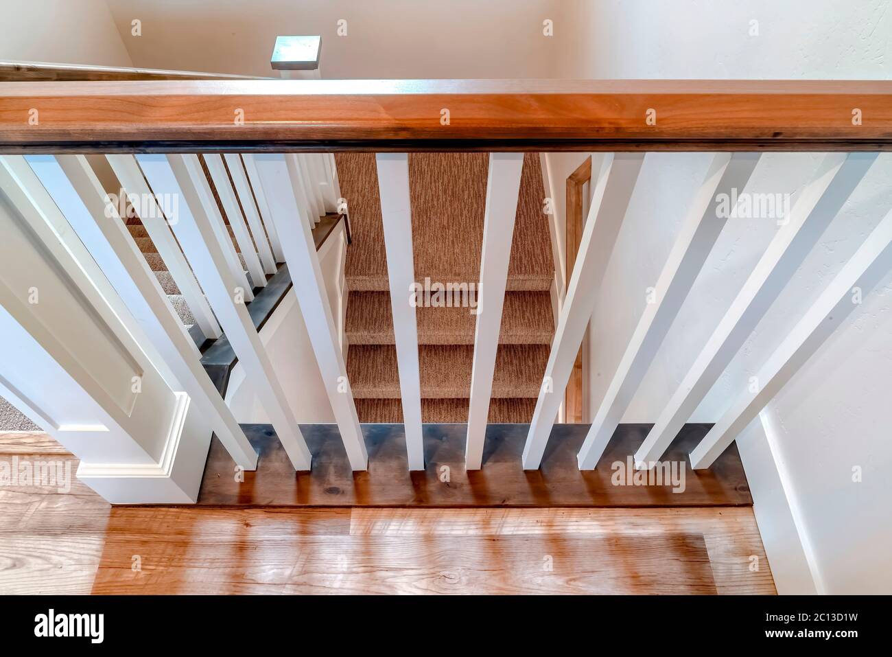 U shaped staircase with white baluster brown handrail and carpet on ...