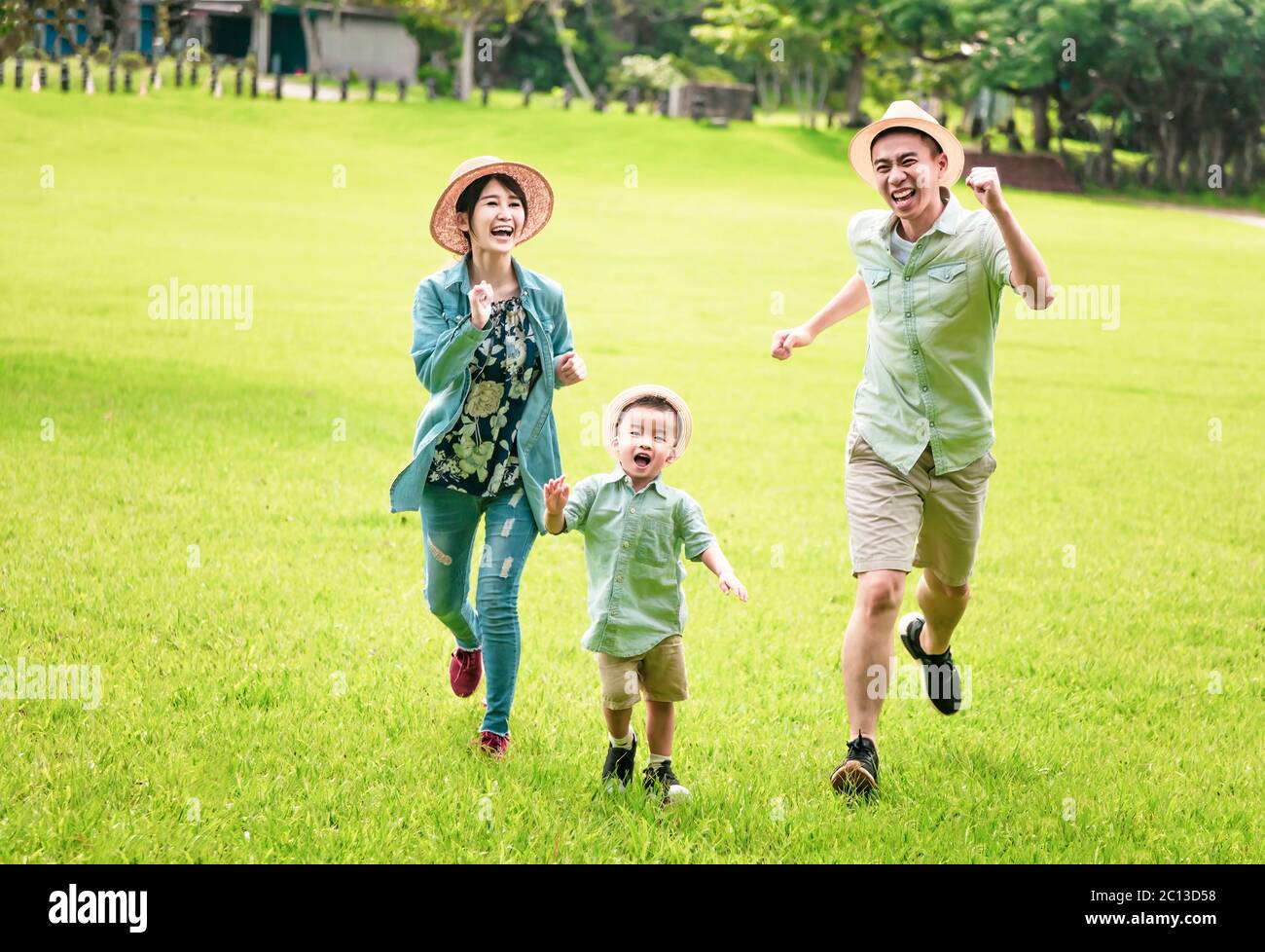 Happy family running together on the grass Stock Photo - Alamy