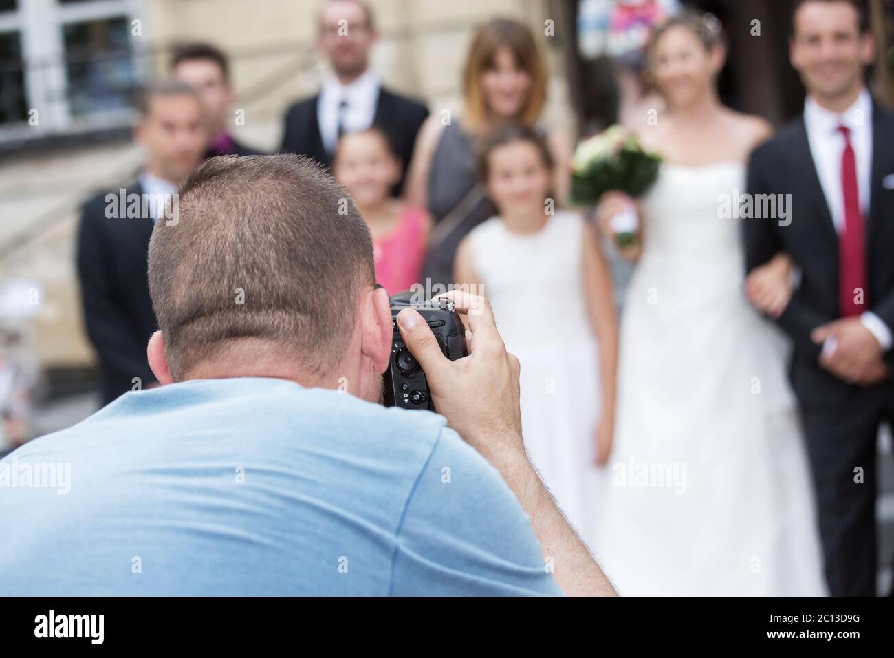 Wedding photographer in action, taking a picture of group of guests ...