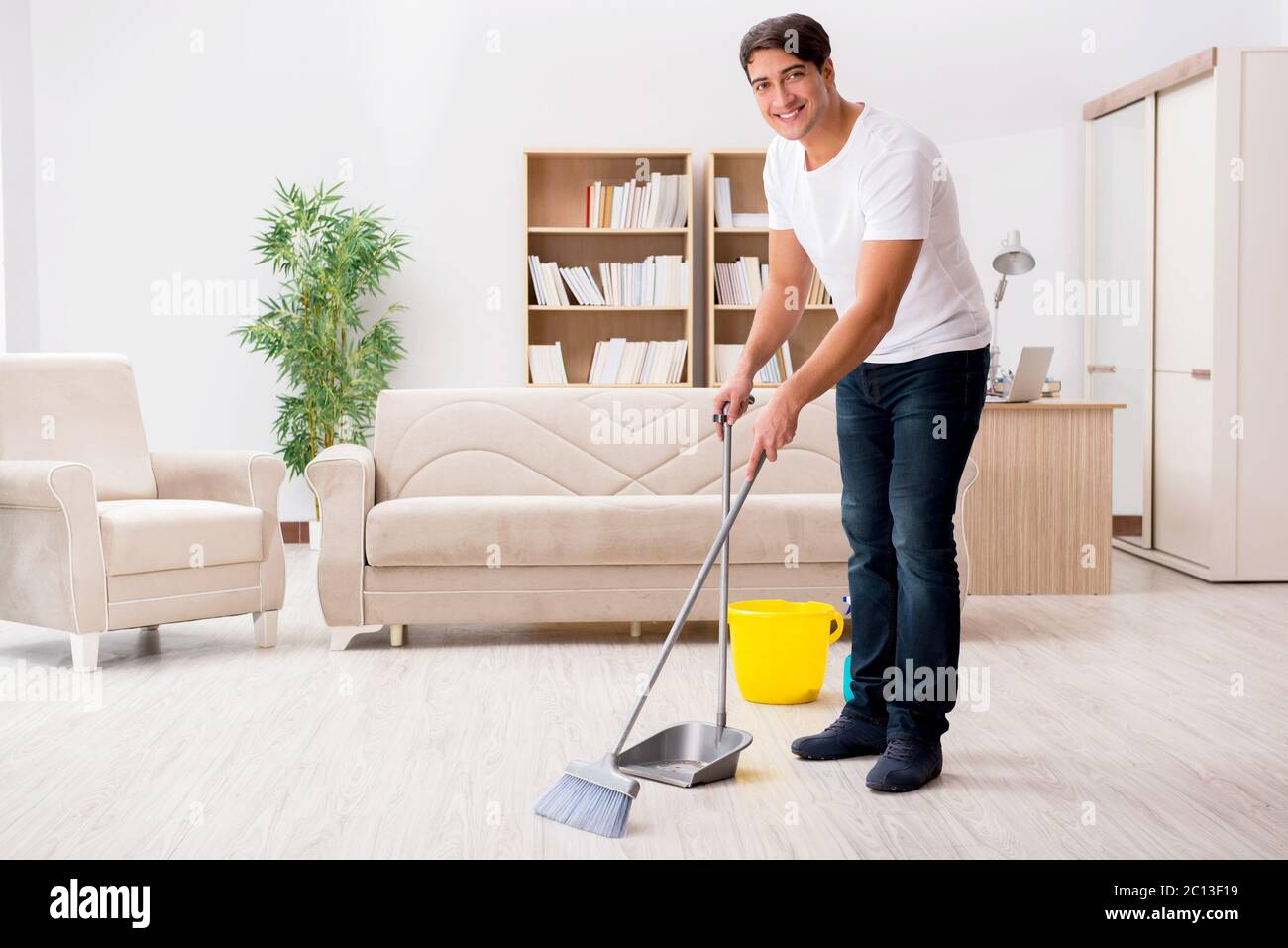 Man cleaning home with broom Stock Photo - Alamy