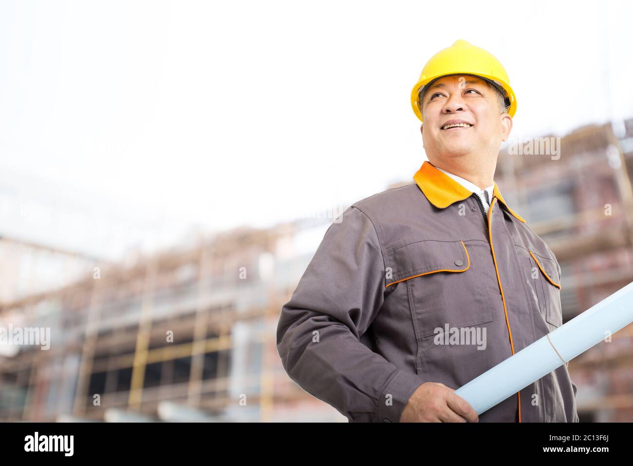 old asian man engineer with blueprint and new construction site Stock ...