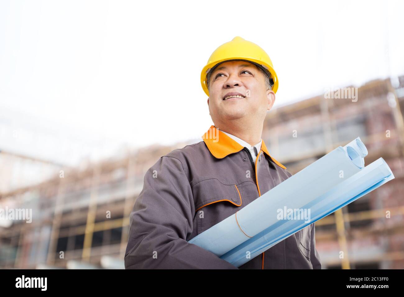 old asian man engineer with blueprint and new construction site Stock ...
